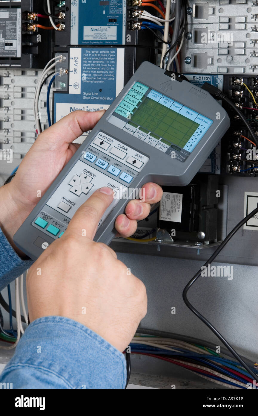 Male technician wiring electronics and wire into a control panel ...