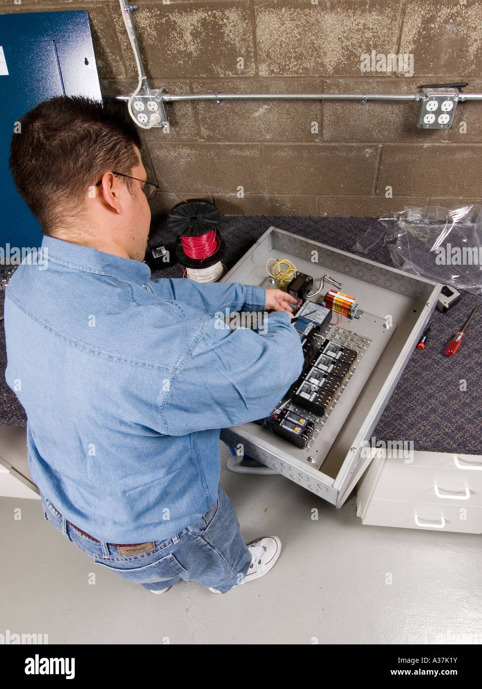 Male technician wiring electronics and wire into a control panel ...