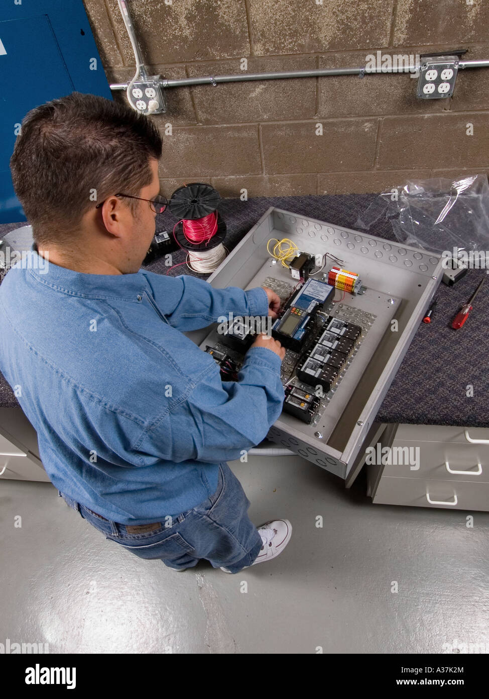 Male technician wiring electronics and wire into a control panel ...