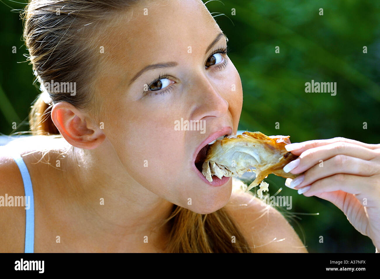 Frau isst ein gegrilltes Haehnchen, woman eating grilled chicken Stock ...