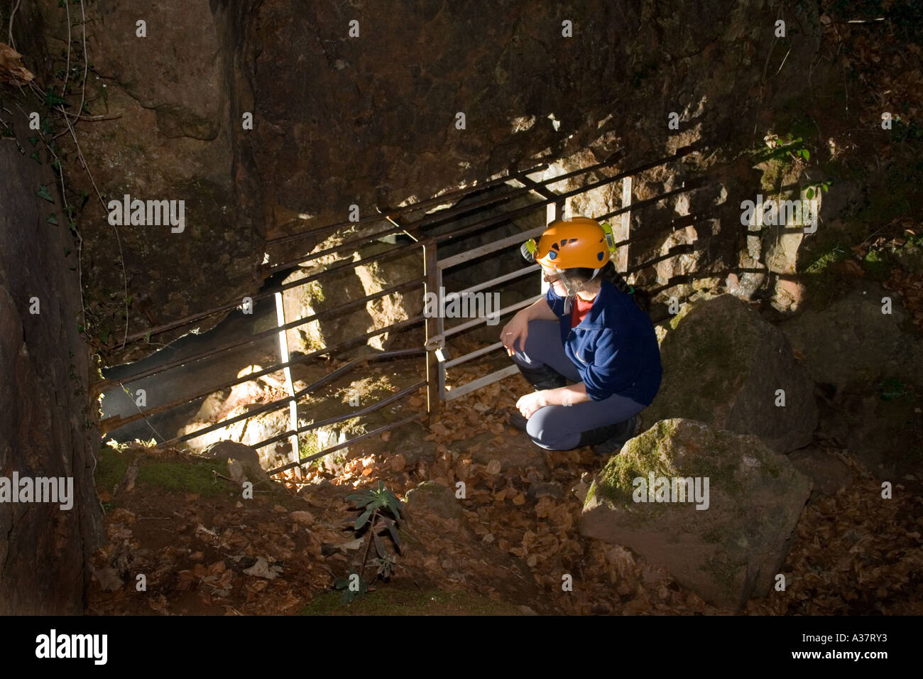 Female caver looking at a bat grilled gate on a cave Wales UK Stock ...