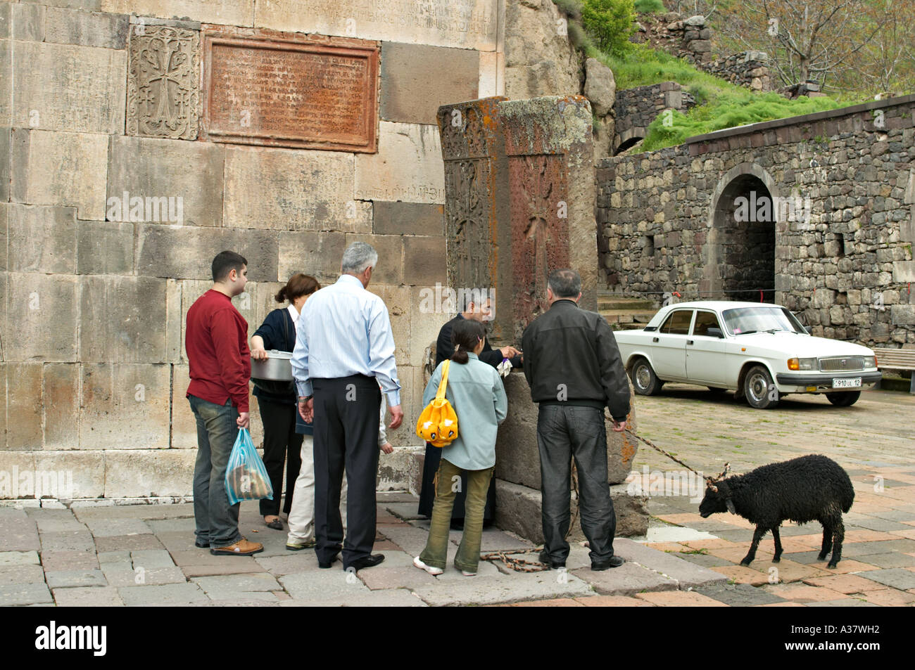 ARMENIA Geghard Priest bless sheep outside monastery in gorge setting ...