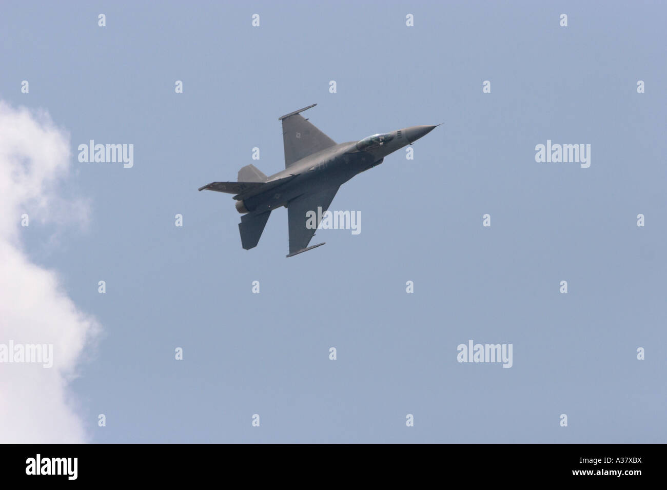 An F 16 Fighting Falcon flying and making a tight turn amidst blue sky ...