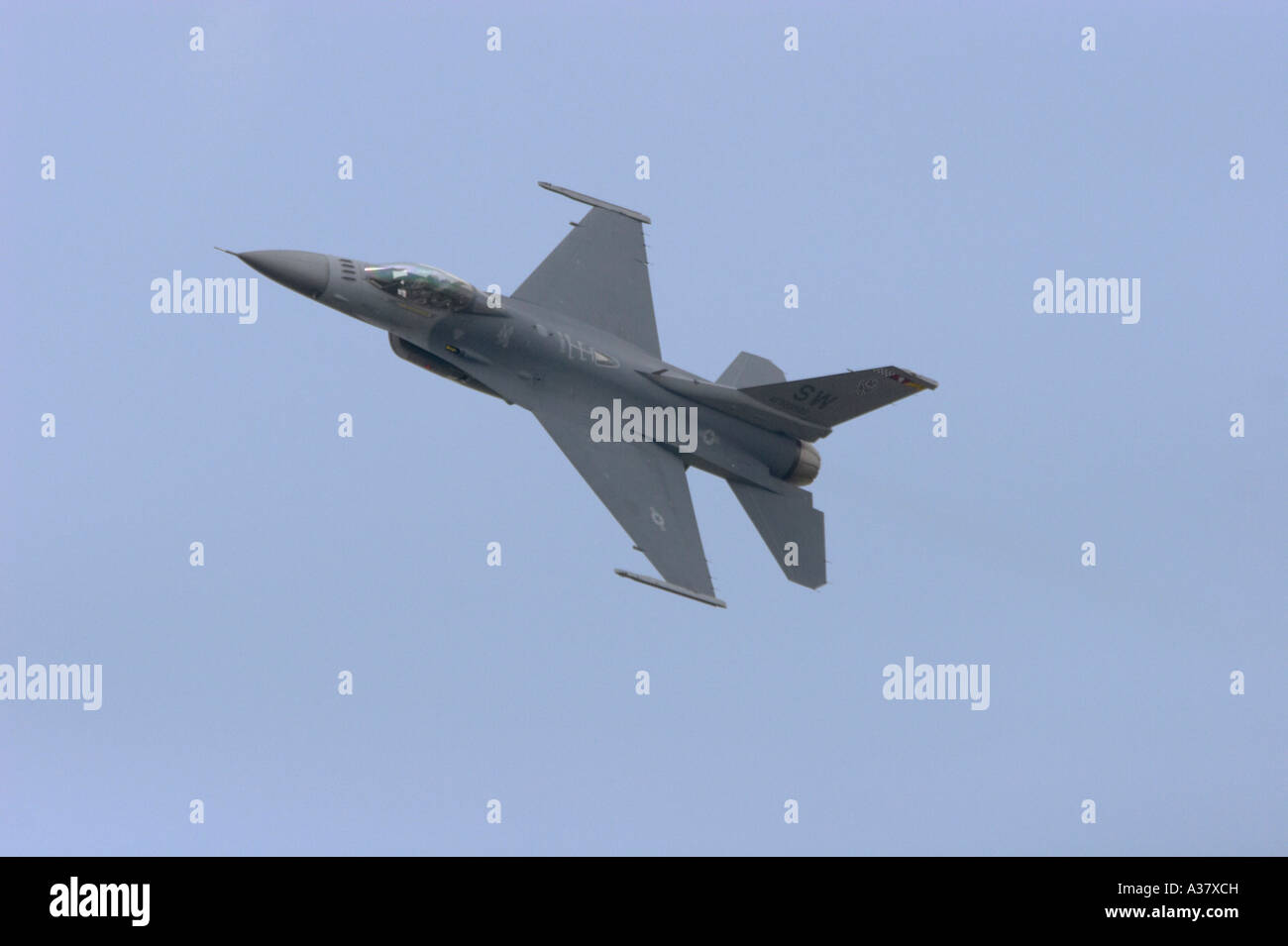 An F 16 Fighting Falcon flying in a tight turn amidst blue sky and ...