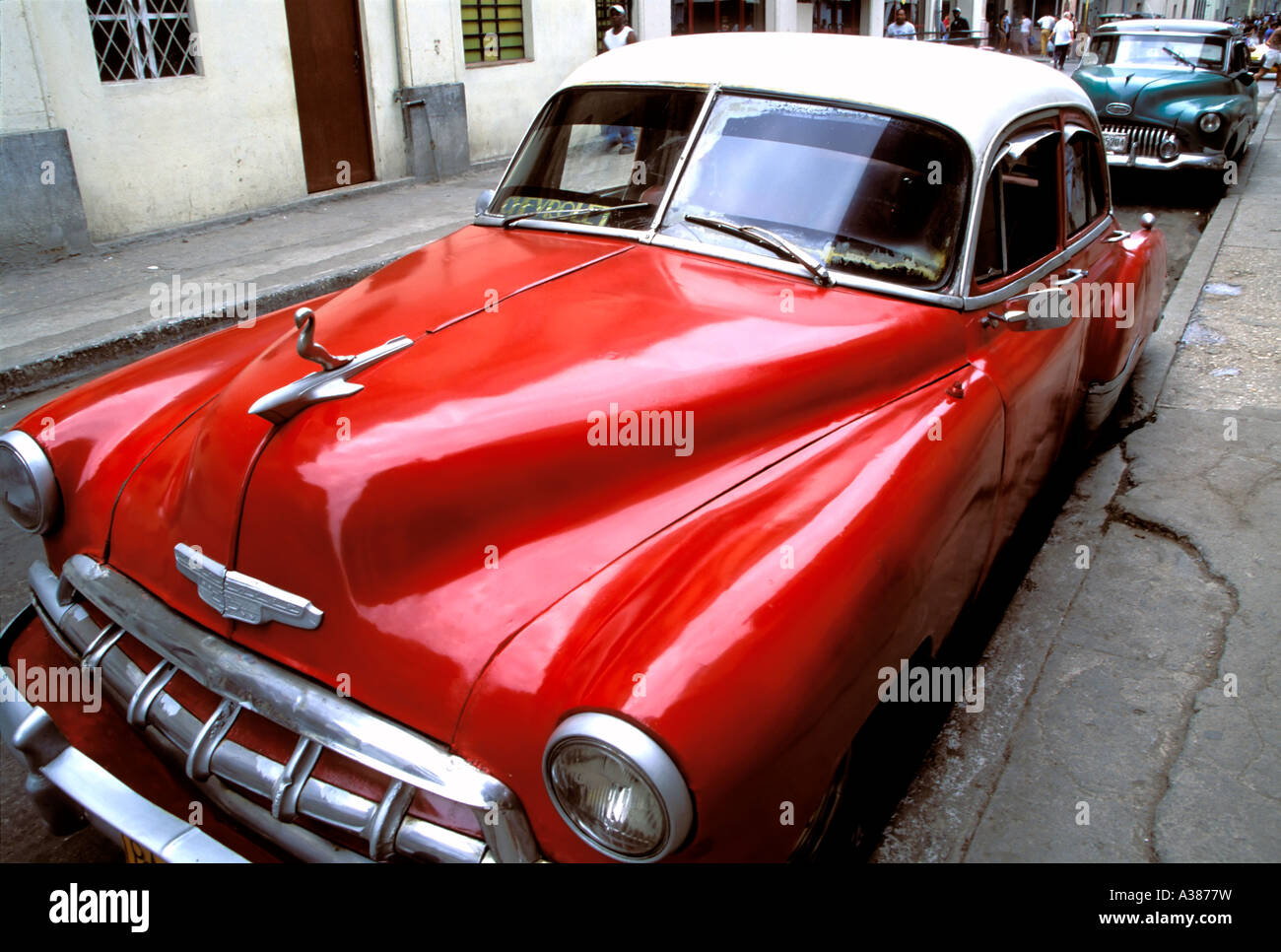 A shiny red classic American car with a white top sits parked in Havana ...