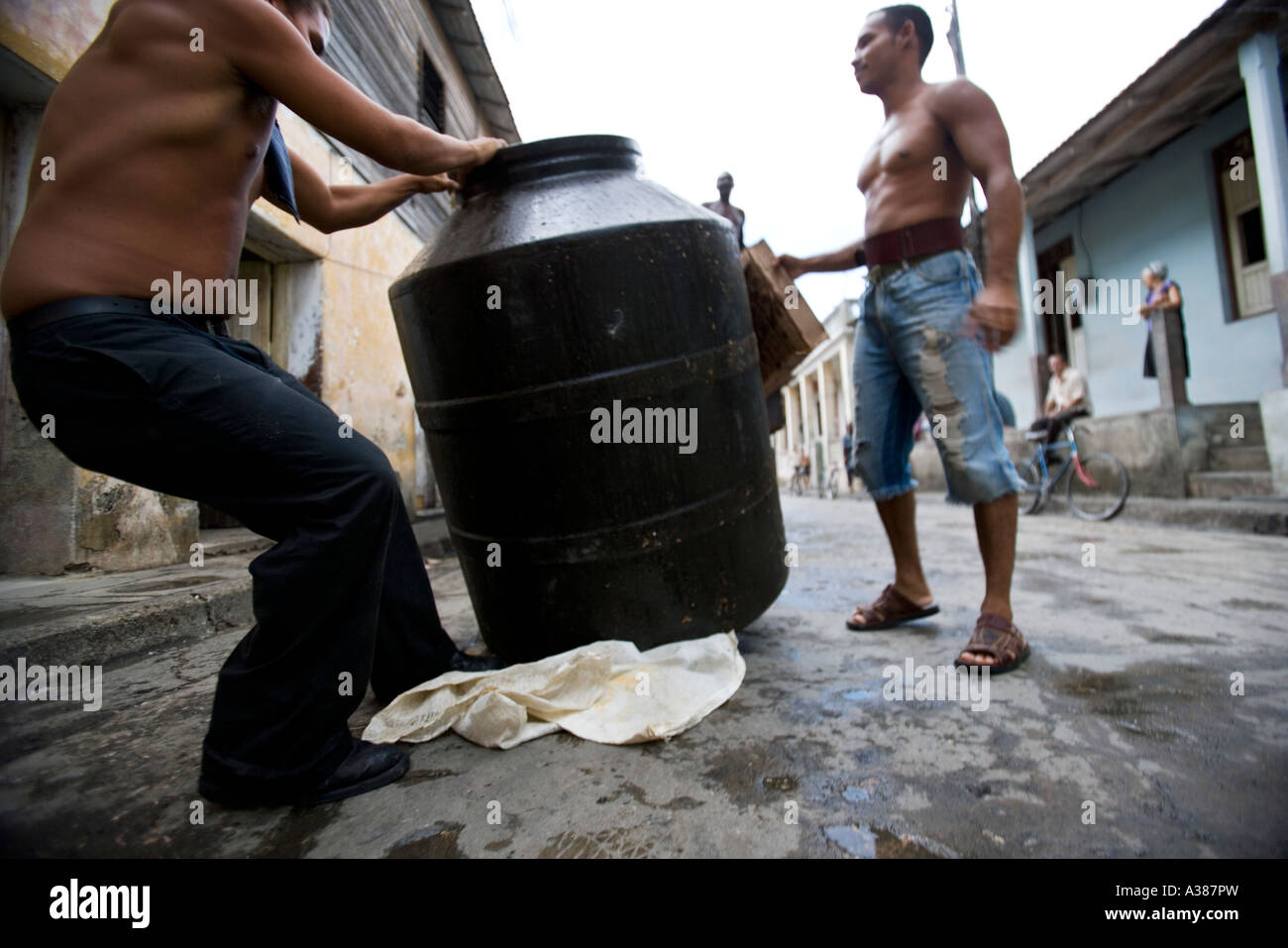 Cuban workers move a water tank in Baracoa Stock Photo - Alamy