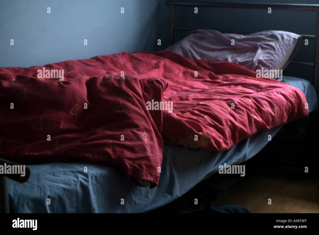 An unmade bed in a messy bedroom Stock Photo - Alamy