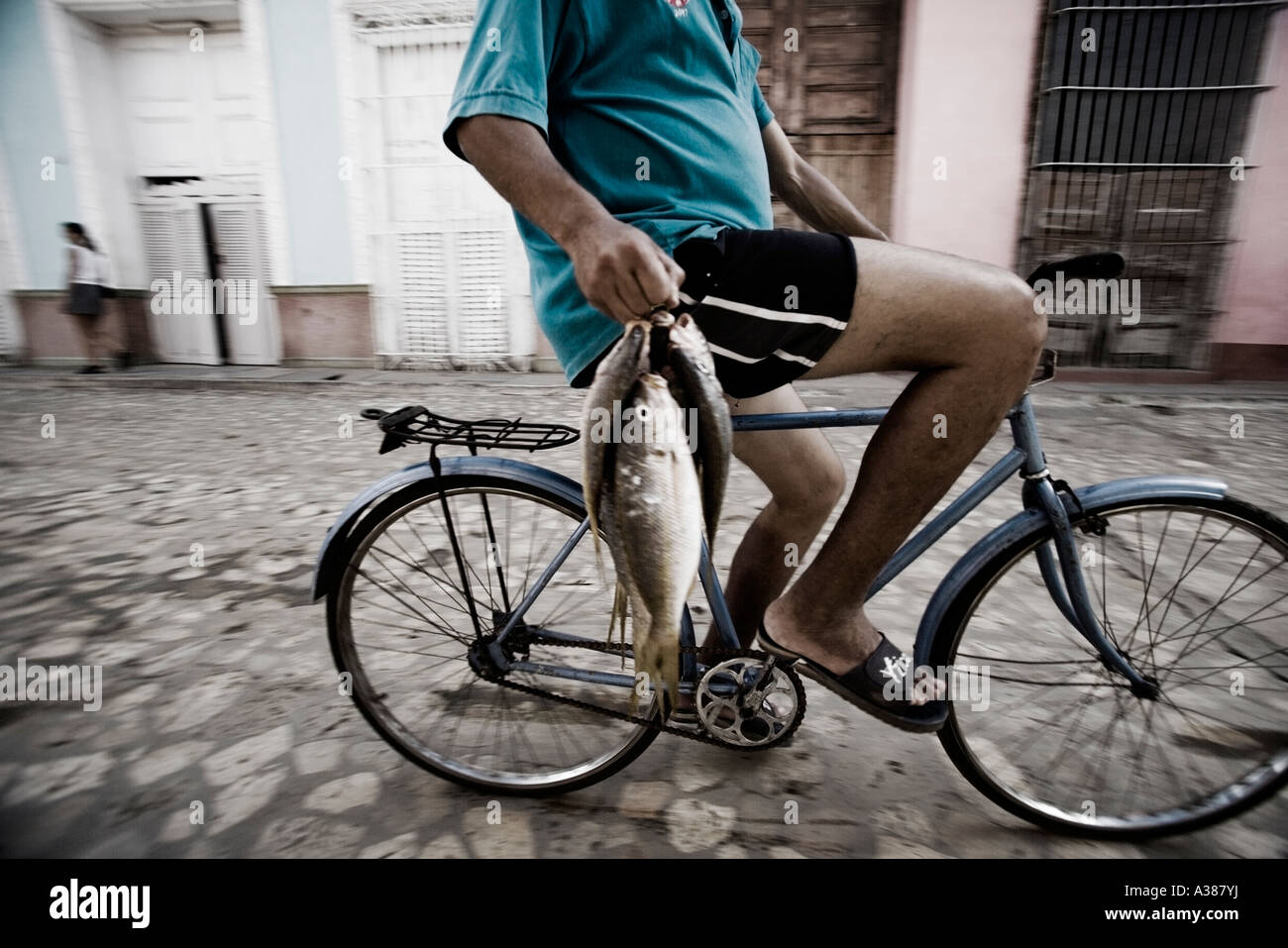 A man carries fish while riding a bicycle in Trinidad Stock Photo - Alamy