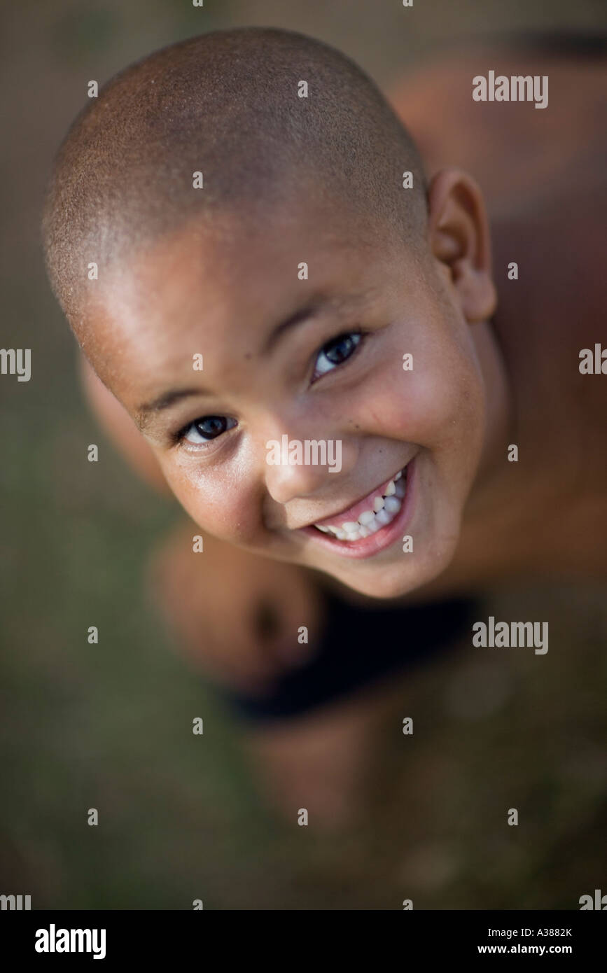 A Cuban boy with a shaved head looks up and smiles for the camera Stock ...