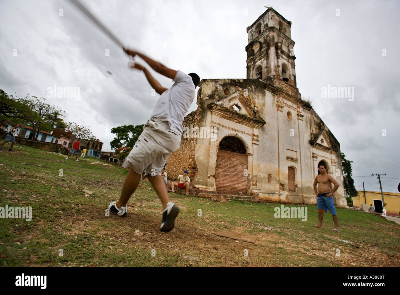 A batter swings and hits a ball in a game of baseball at a church in ...