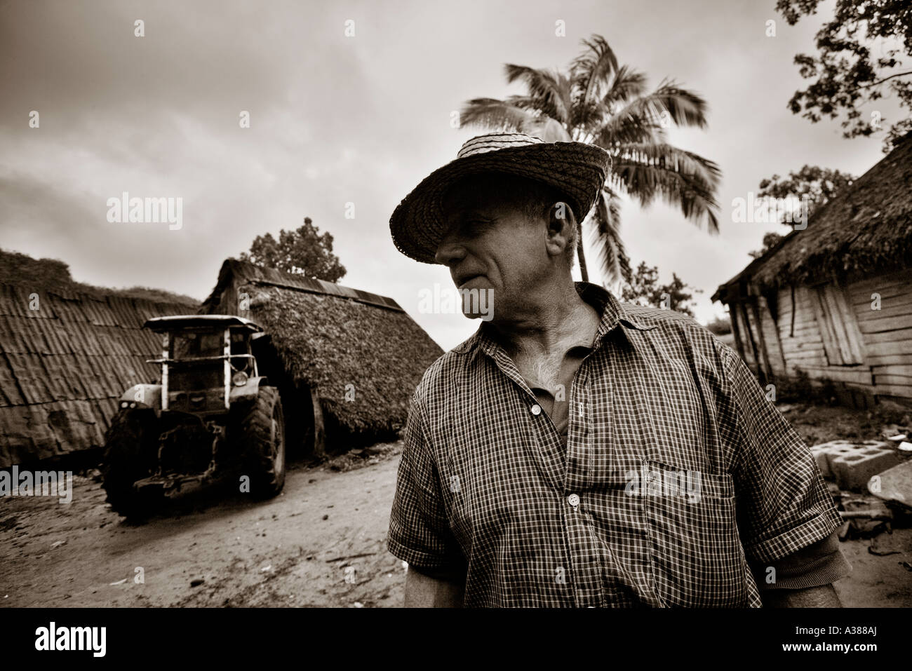 Cuba A Cuban farmer stands set against tractor and barns Stock Photo ...