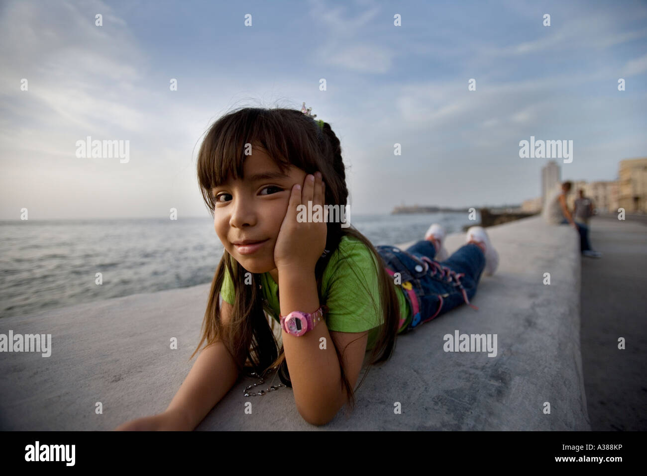 A young Cuban girl relaxes by laying along the seawall next to El ...
