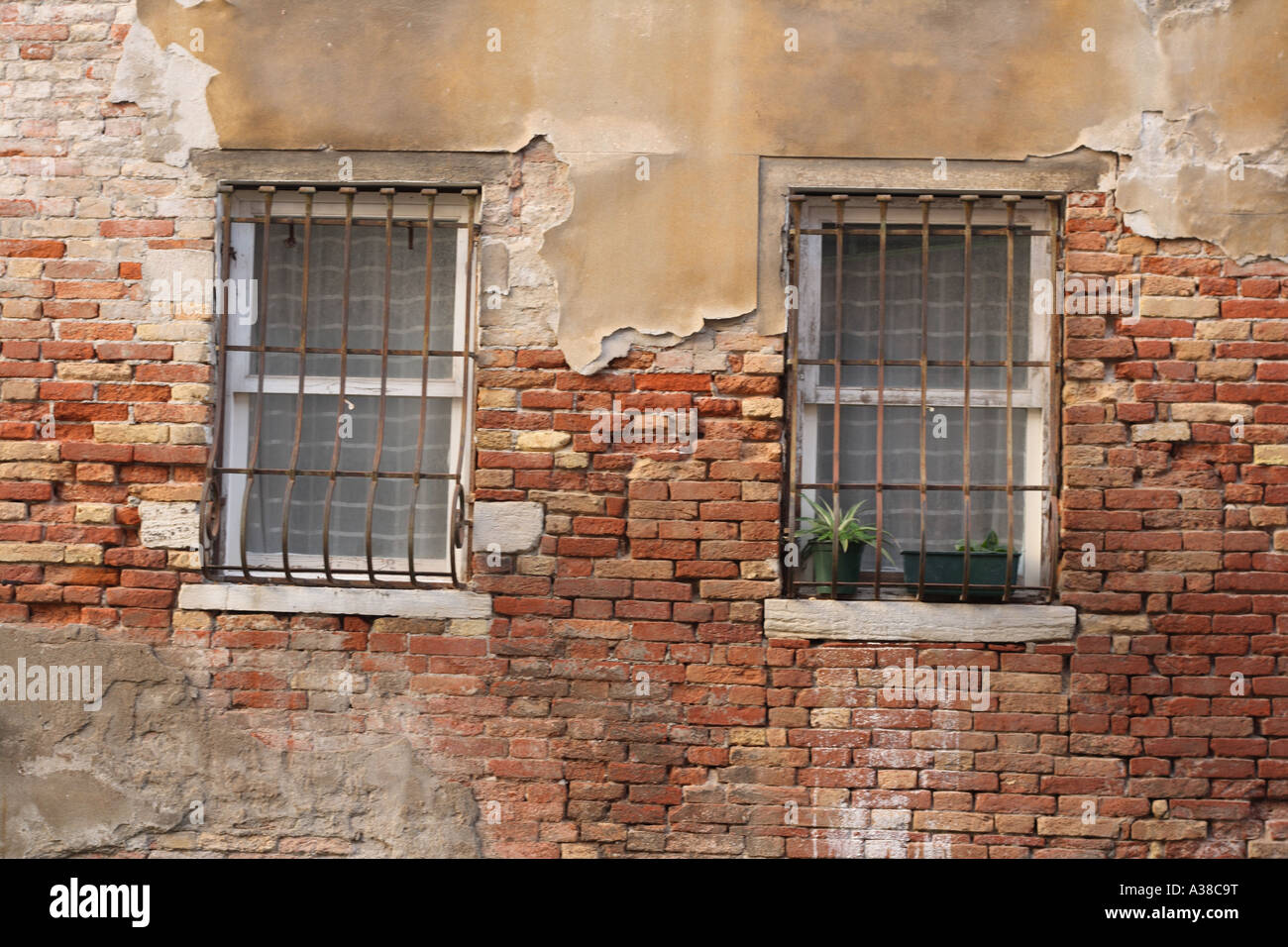 two windows on the side of a house showing erosion from salt water and ...