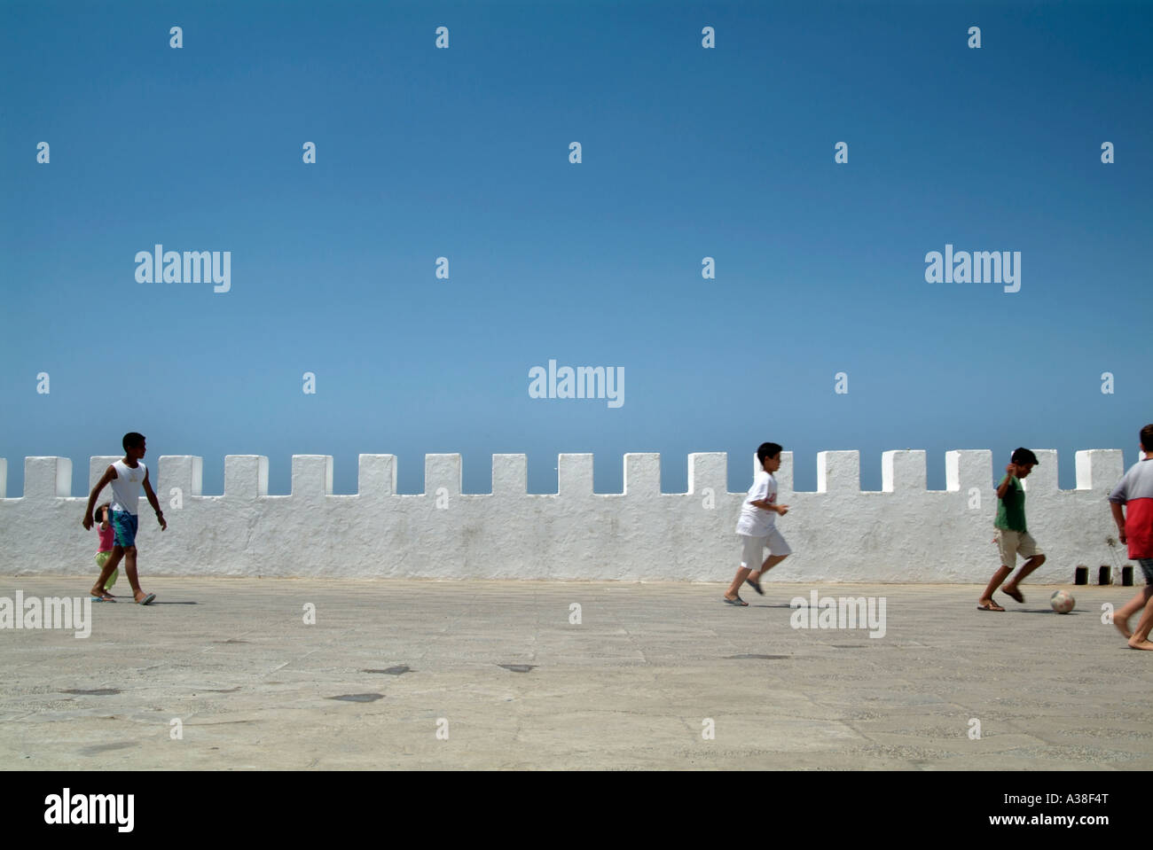 Children playing football in a Medina street by the whitewashed ...