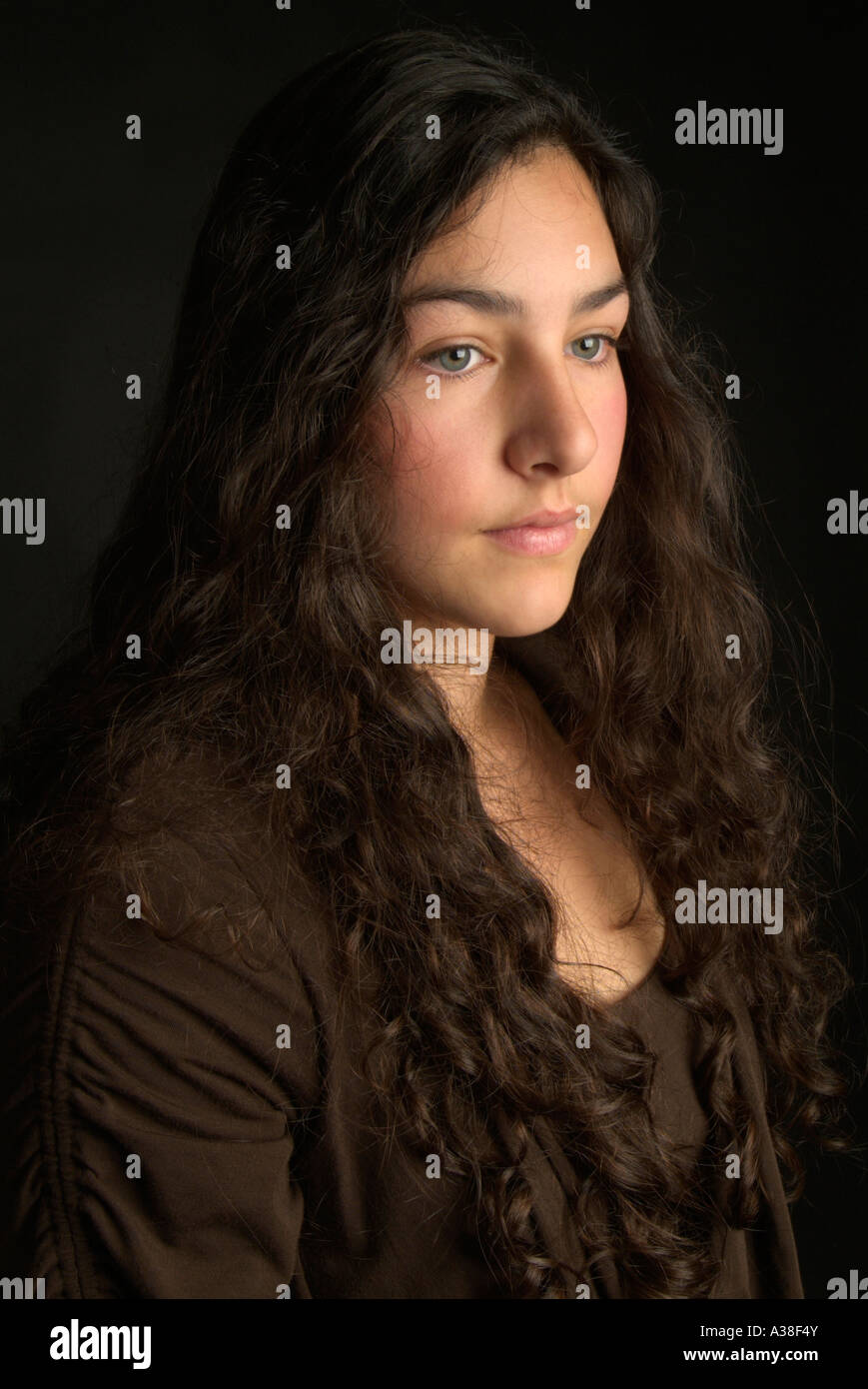 Studio portrait of a beautiful young woman with long curly dark hair ...