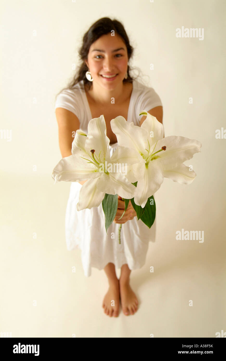 Studio portrait of a smiling young woman wearing white holding out a ...
