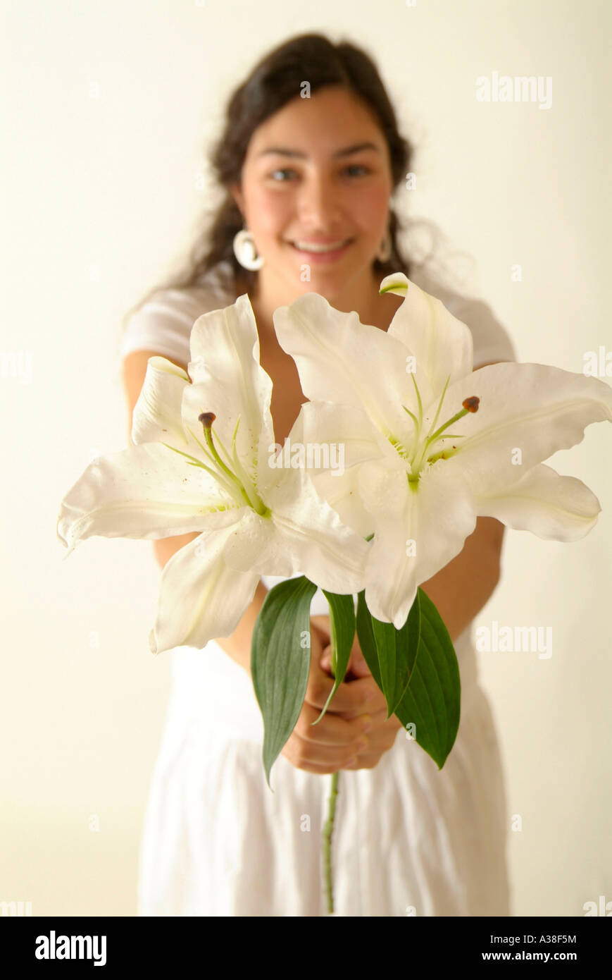 Studio portrait of a smiling young woman wearing white holding out a ...
