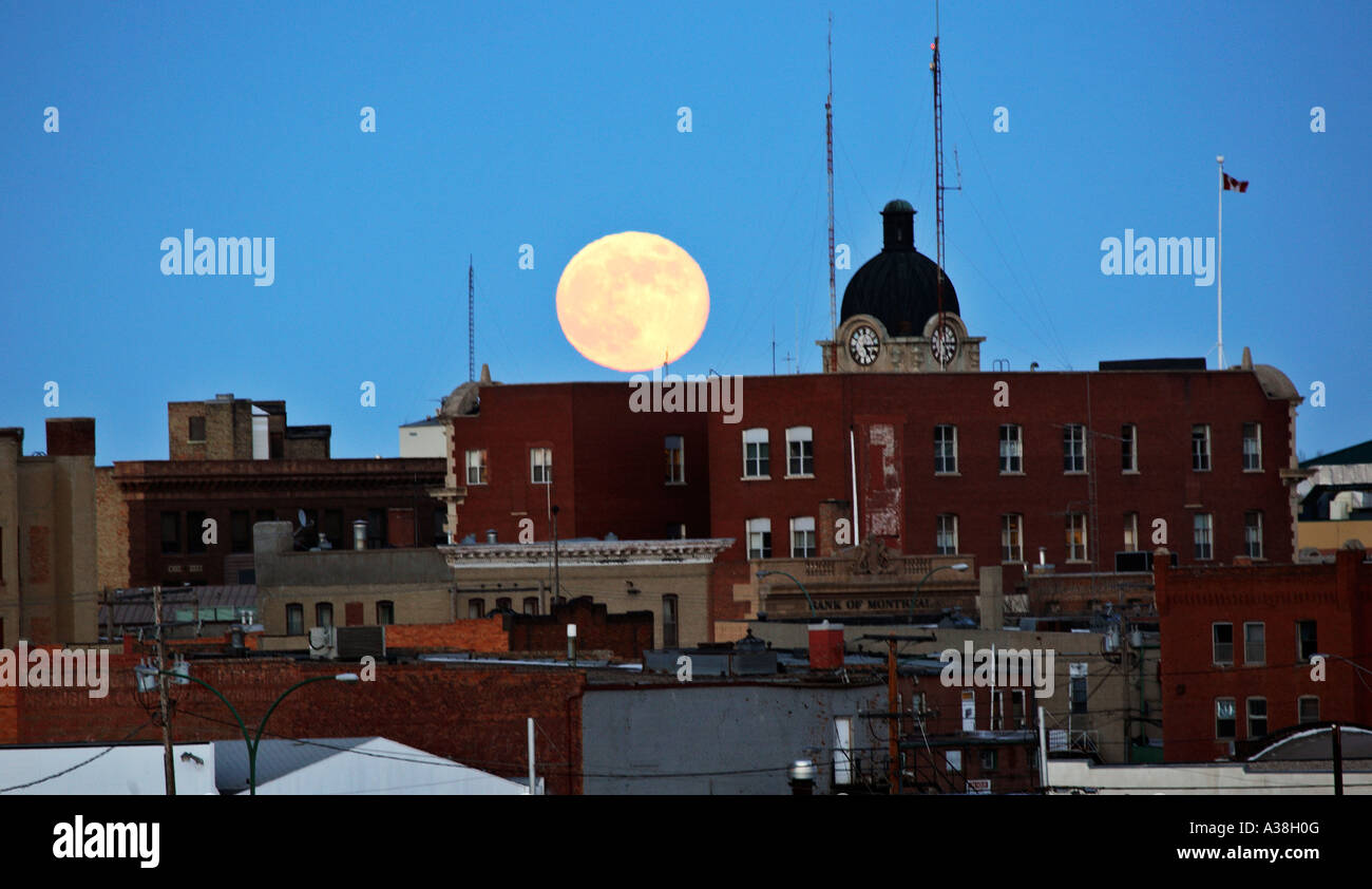full moon rising over buildings Stock Photo - Alamy