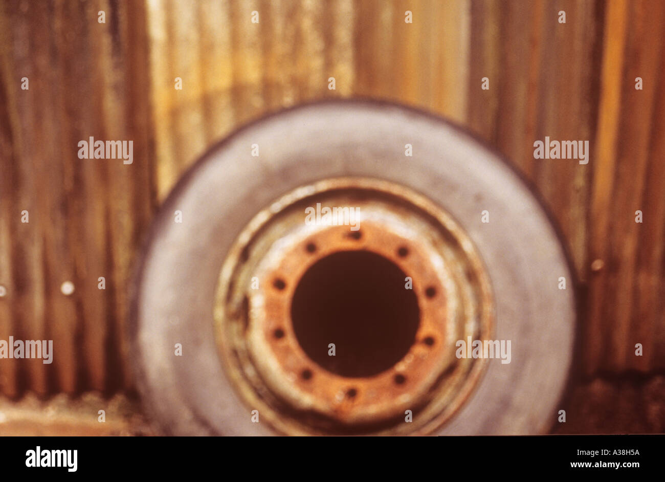 A defocussed large old tyre on a rusty wheelhub leaning against a rusty ...