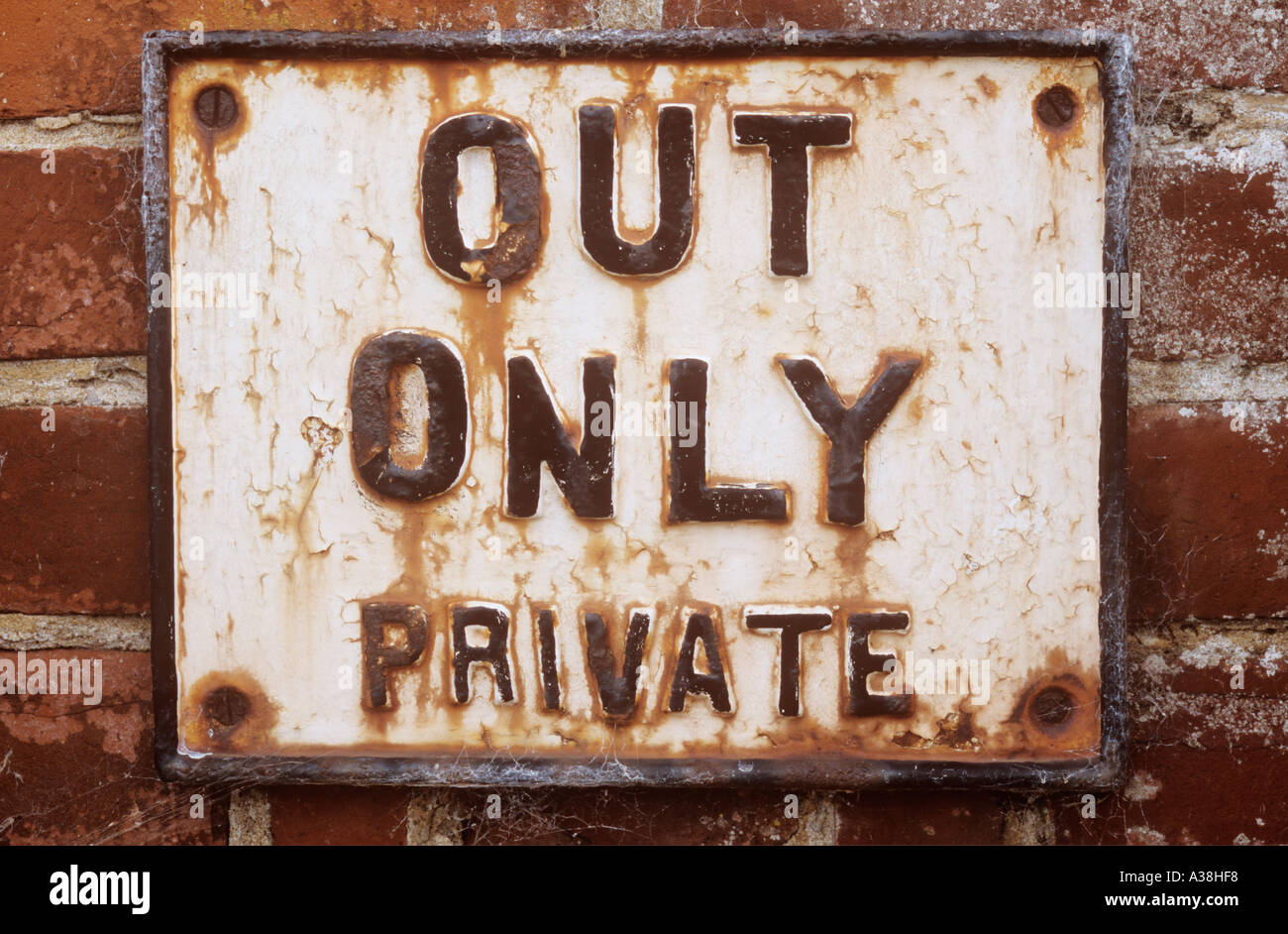 Rusting painted cast iron metal sign attached to brick wall stating Out ...
