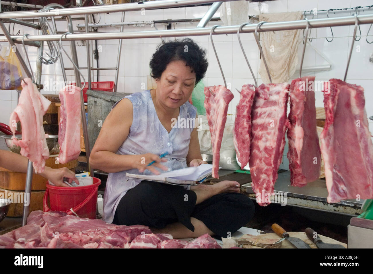 A woman tots up the returns from her butchers stall in Ben Thanh Market ...