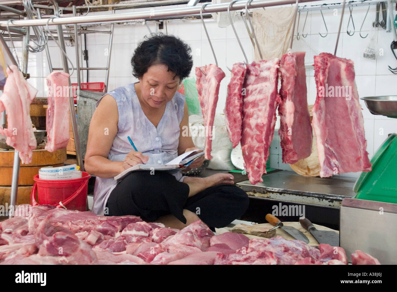 A woman tots up the returns from her butchers stall in Ben Thanh Market ...