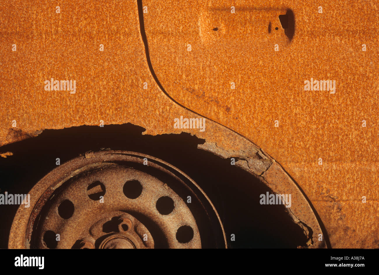 Detail of a rusted burnt out vehicle in the sun showing part of a door ...