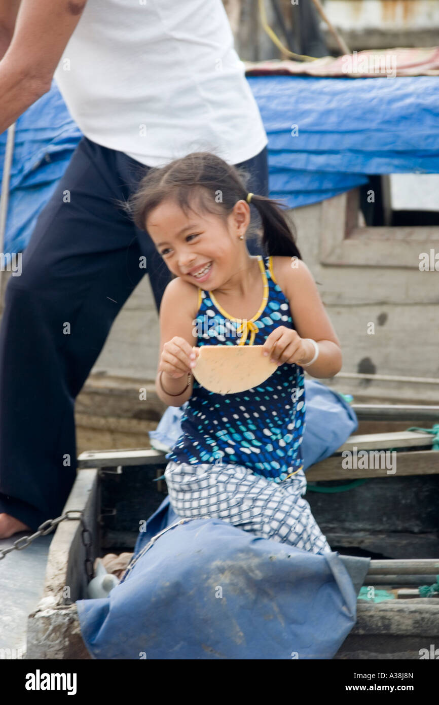 Little girl eating a rice cracker at the floating market near Can Tho ...