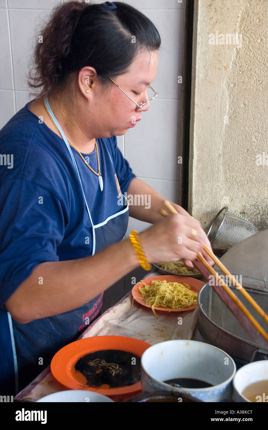Woman cooking noodles in the market in George Town Penang Stock Photo ...
