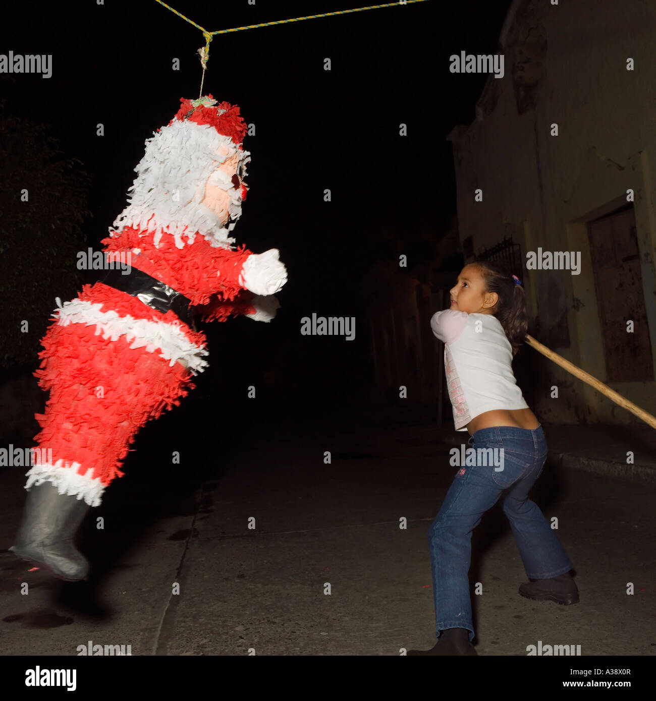 A young girl hits a Santa Claus Father Christmas pinata with a stick in ...