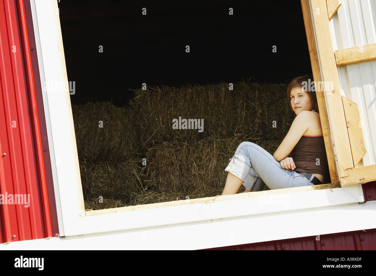 Teen looking out hay loft window Stock Photo - Alamy