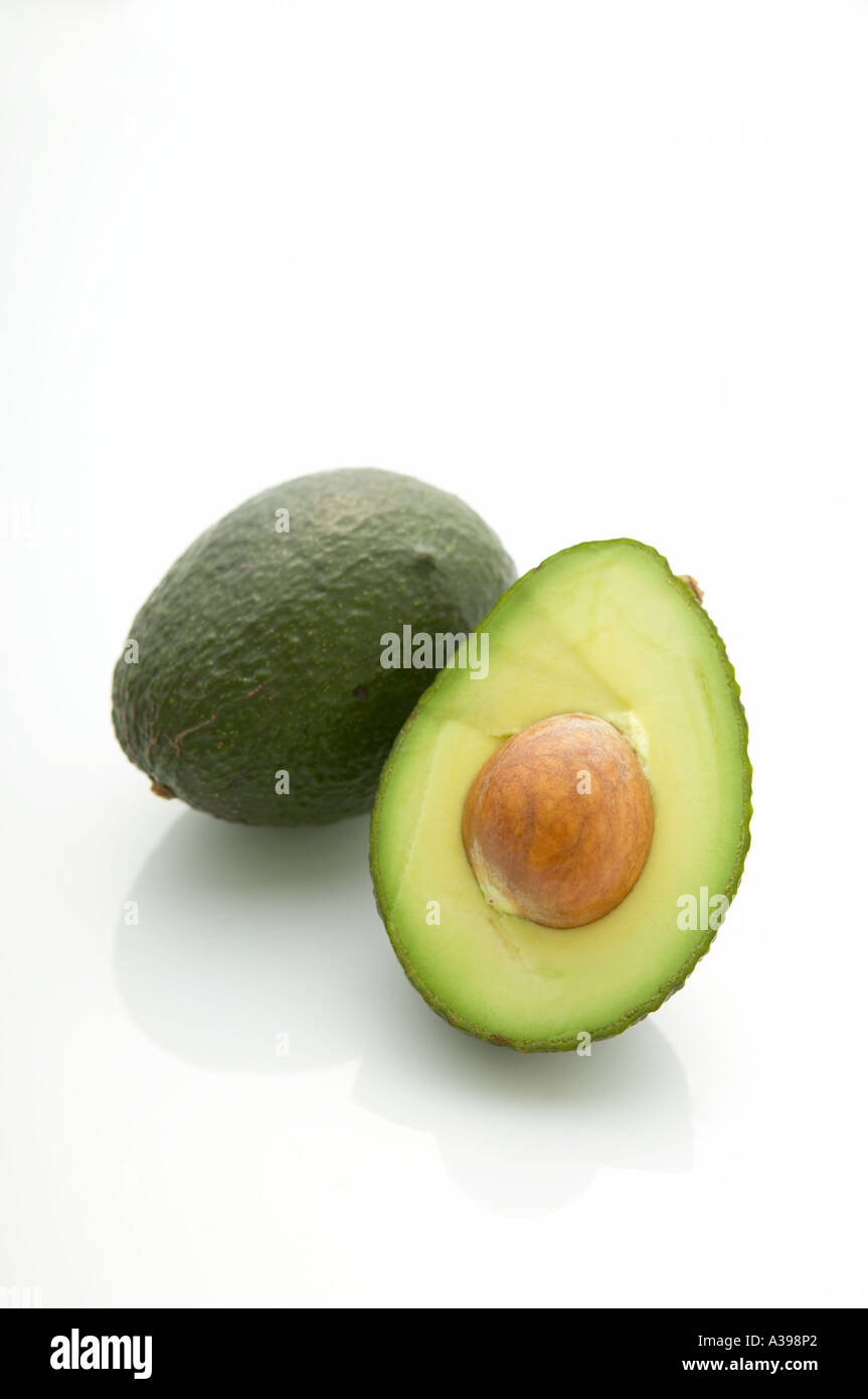 A halved avocado and the whole one on white surface Stock Photo - Alamy