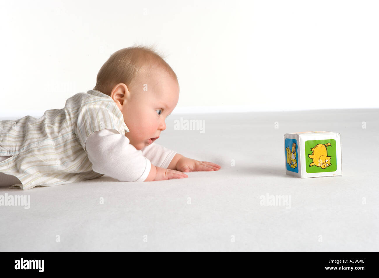 Blond baby boy reaching for a toy Stock Photo - Alamy
