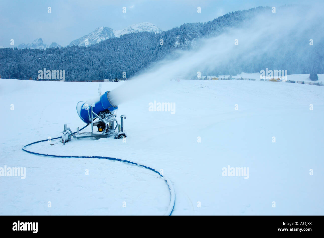 A snow cannon in action on a ski piste in the early morning Stock Photo ...