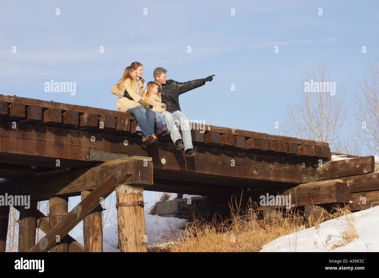 Family sitting on bridge Stock Photo - Alamy