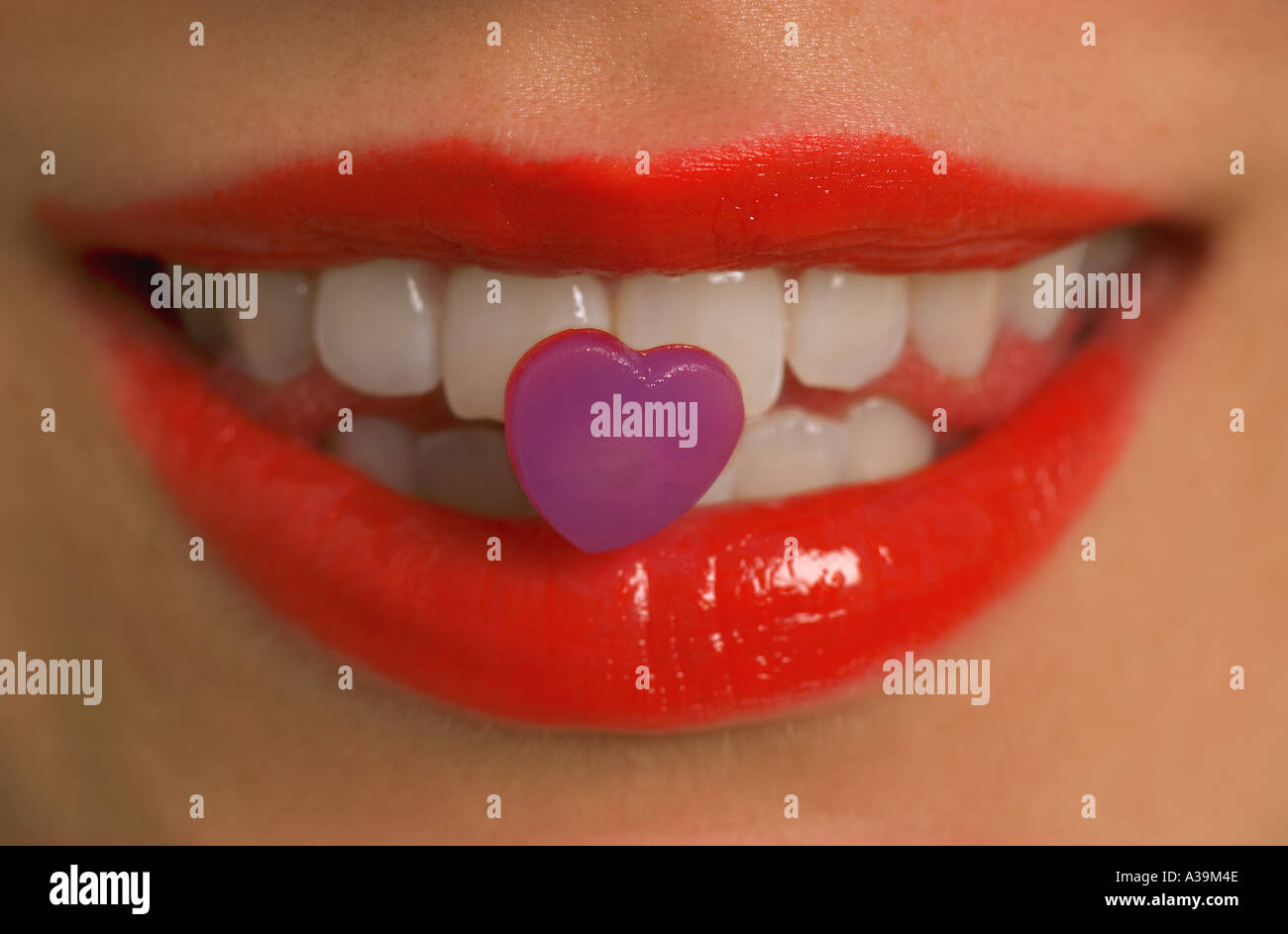 Heart candy stuck on teeth Stock Photo - Alamy