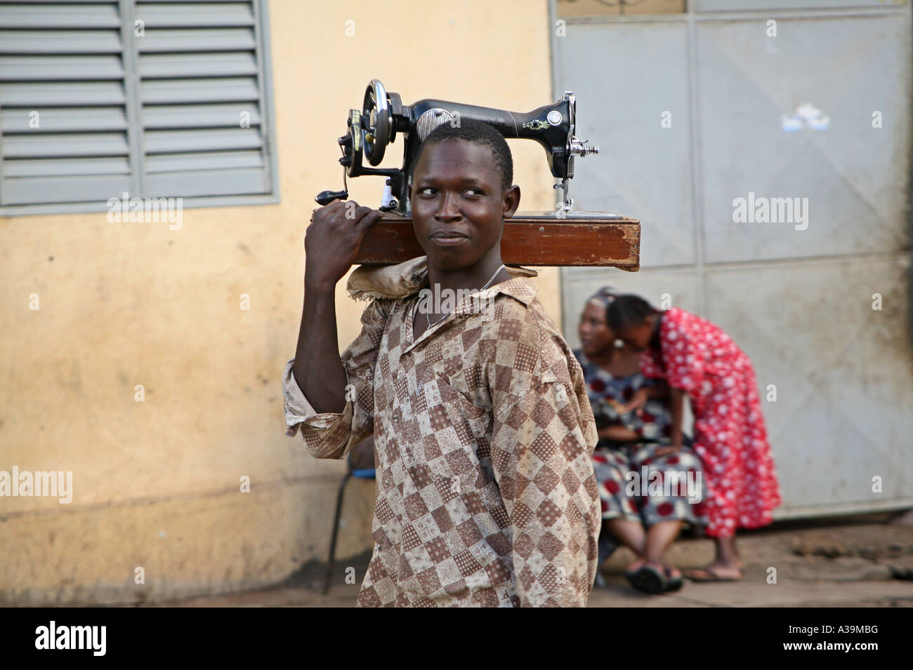 A mobile tailor walking the streets with his sewing machine on his ...