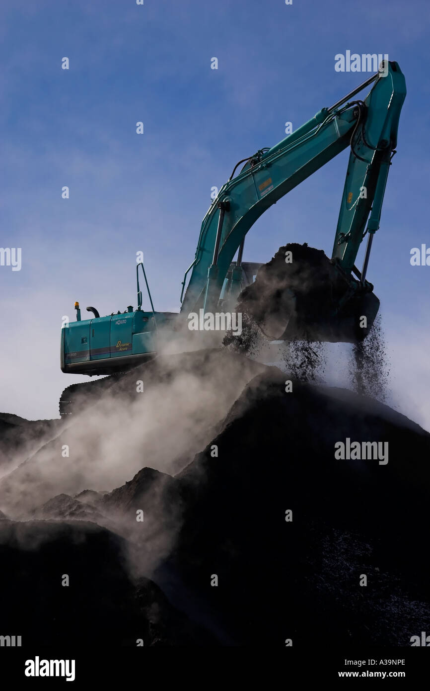 Digger working, throwing up steam in the cold from a warm pile of soil ...