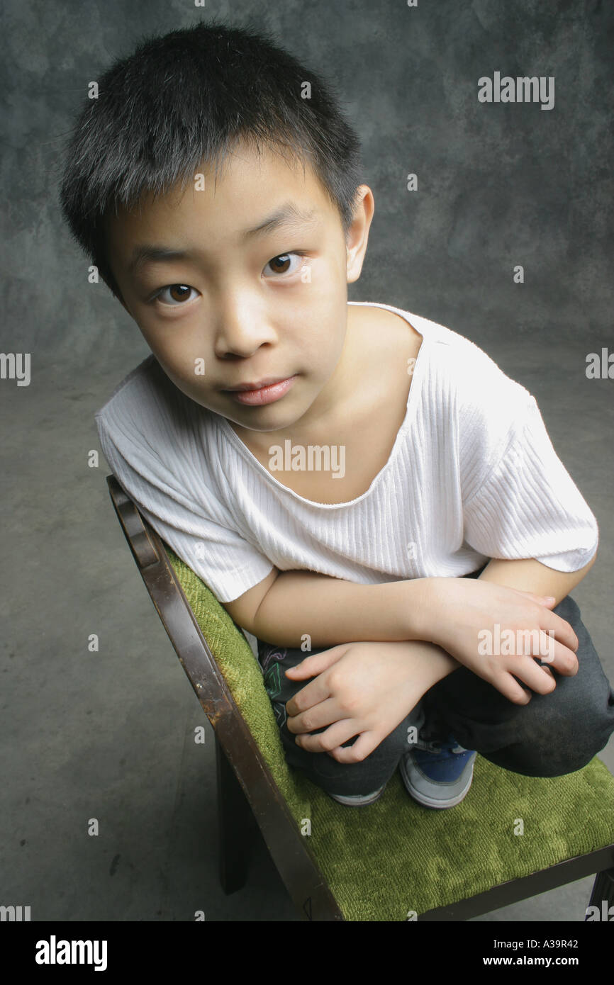 Young boy perched on chair Stock Photo - Alamy