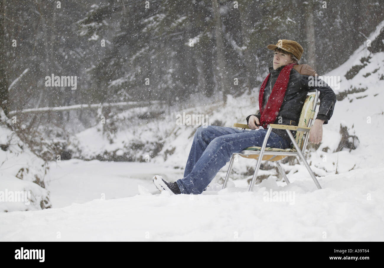 Man sitting on chair in snow Stock Photo - Alamy
