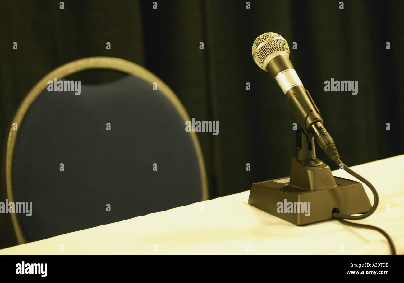 Empty chair and table with microphone Stock Photo - Alamy