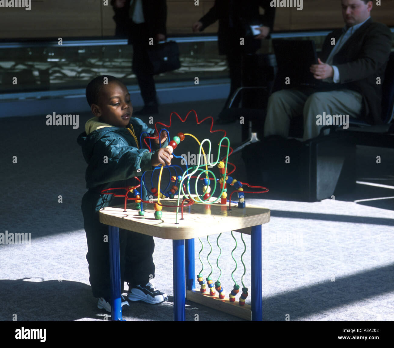 March 15th 2002 A young boy plays with a puzzle whilst behind him a man ...