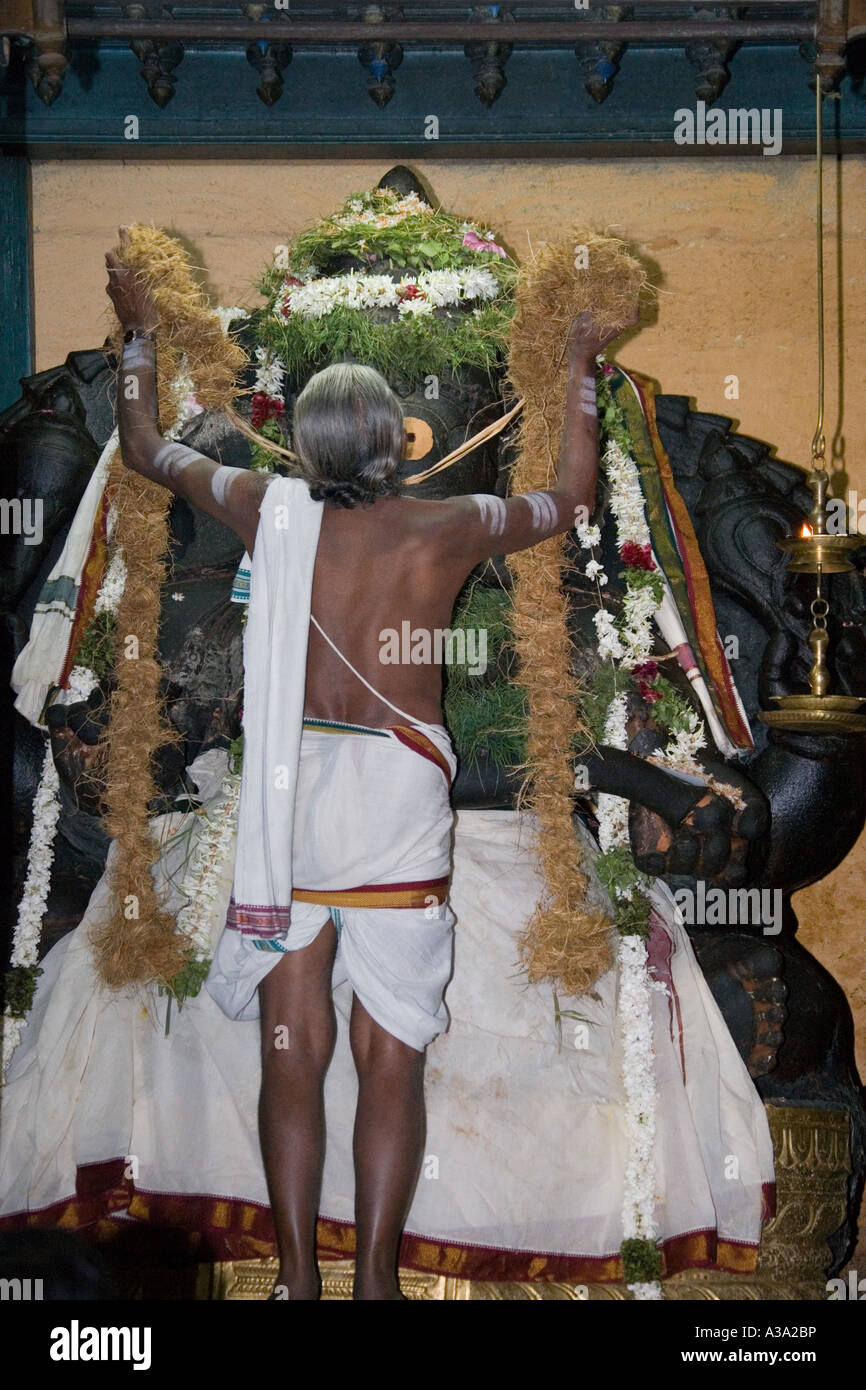 Hindu man putting a garland around a statue of the Hindu god Ganesha in ...