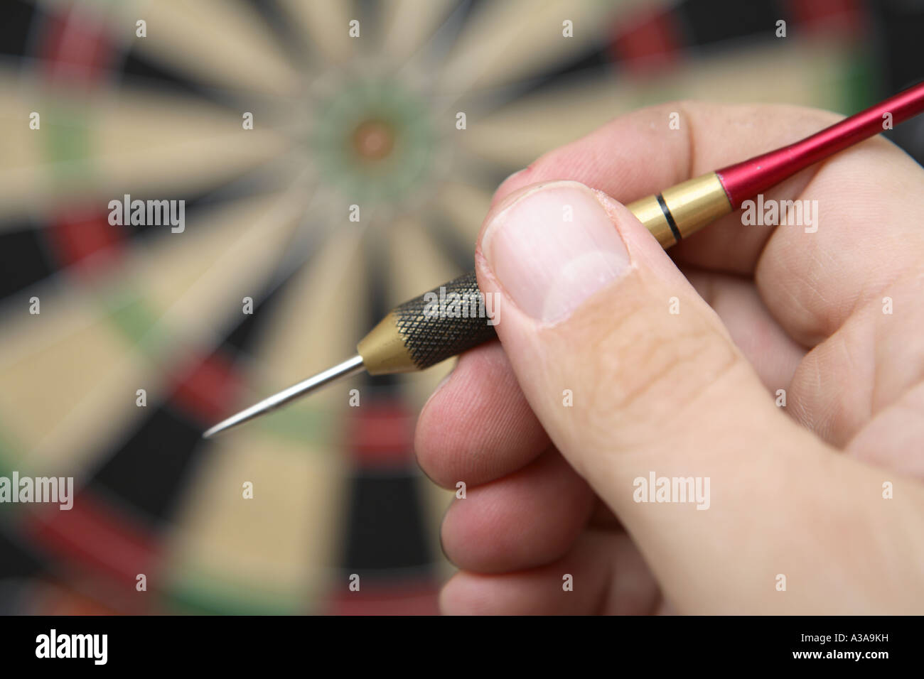 Hand holding dart with dart board in background Stock Photo - Alamy