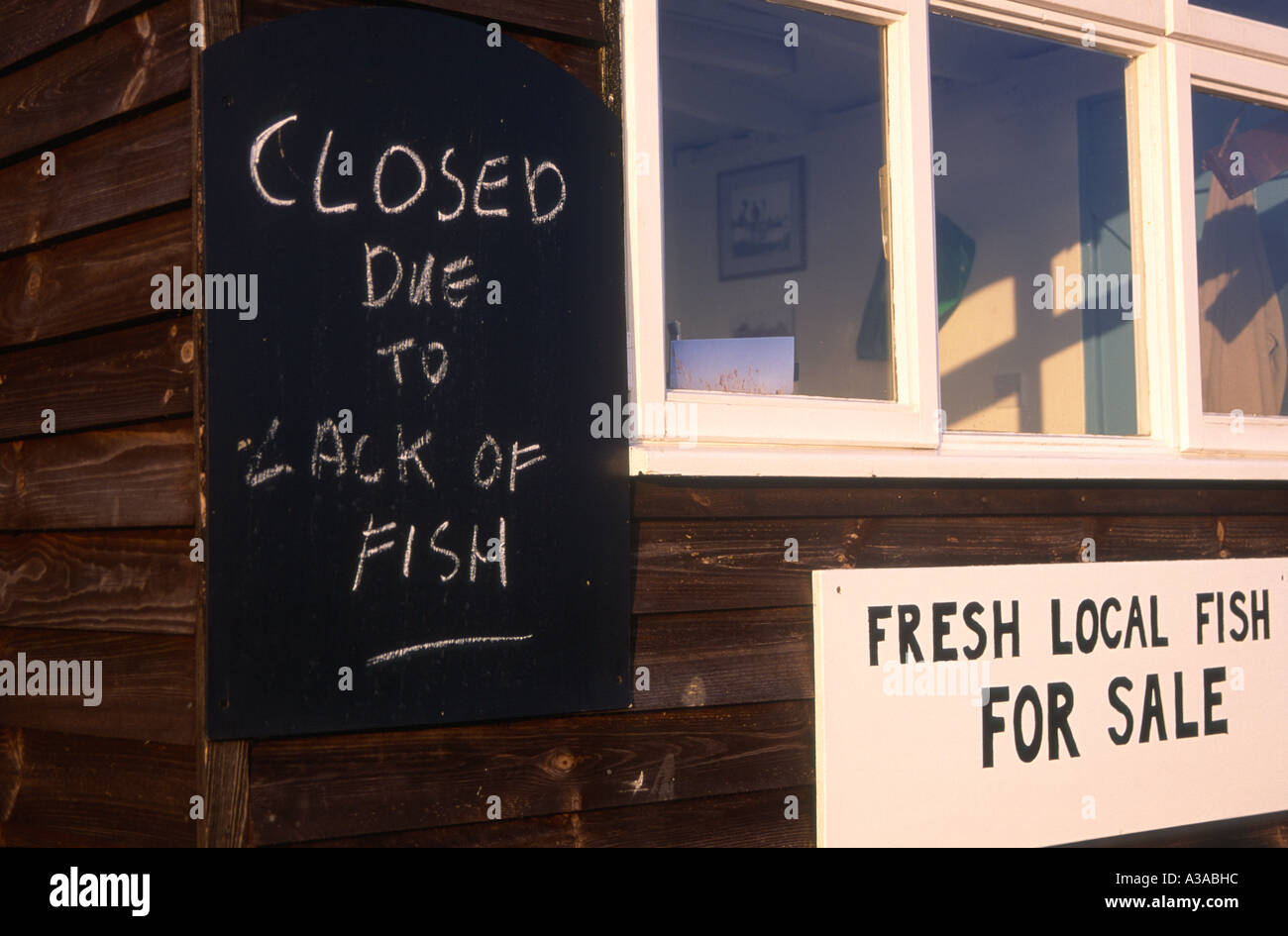 Blackboard sign on small coastal fish shed saying 'closed due to lack ...