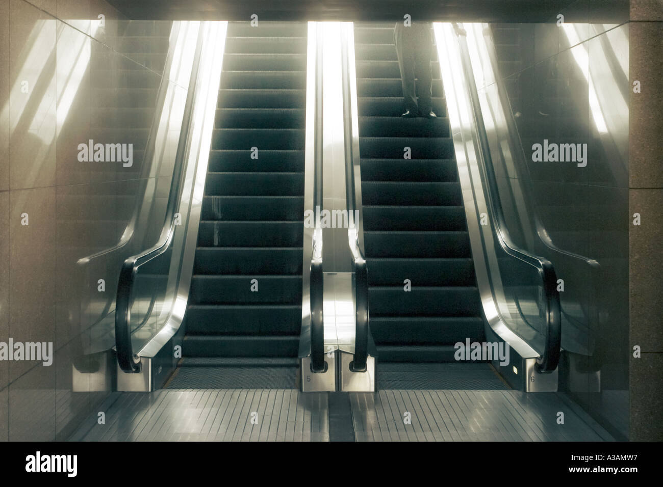Man descends escalator. Defused light, reflection from stainless steel ...