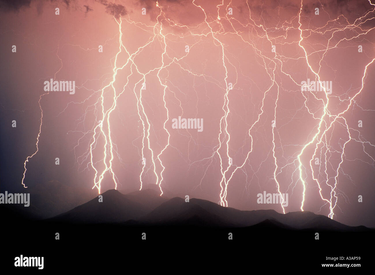 Lightning bolts crash down from storm clouds over the Rincon mountains ...