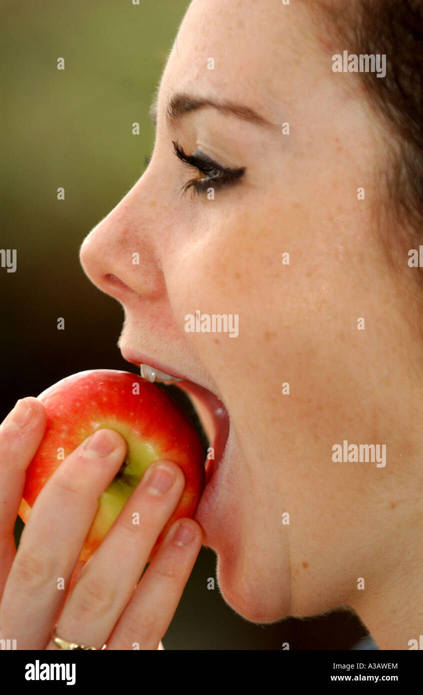 Young woman teenager biting into a Pink Lady apple Stock Photo - Alamy