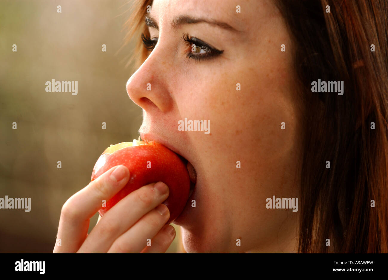 Young woman teenager biting into a Pink Lady apple Stock Photo - Alamy