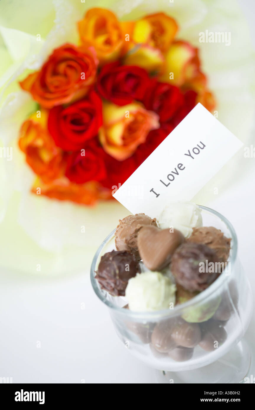 A bouquet and greetings note and a glass of chocolates in white ...